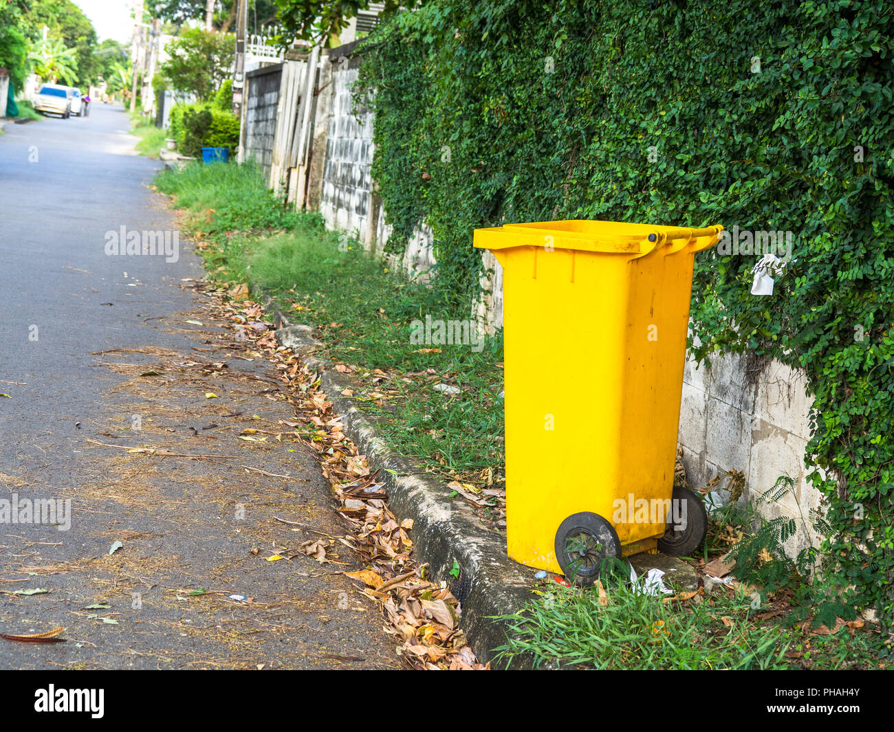 Yellow bins are placed on the side of the road in the village. Trash is ...