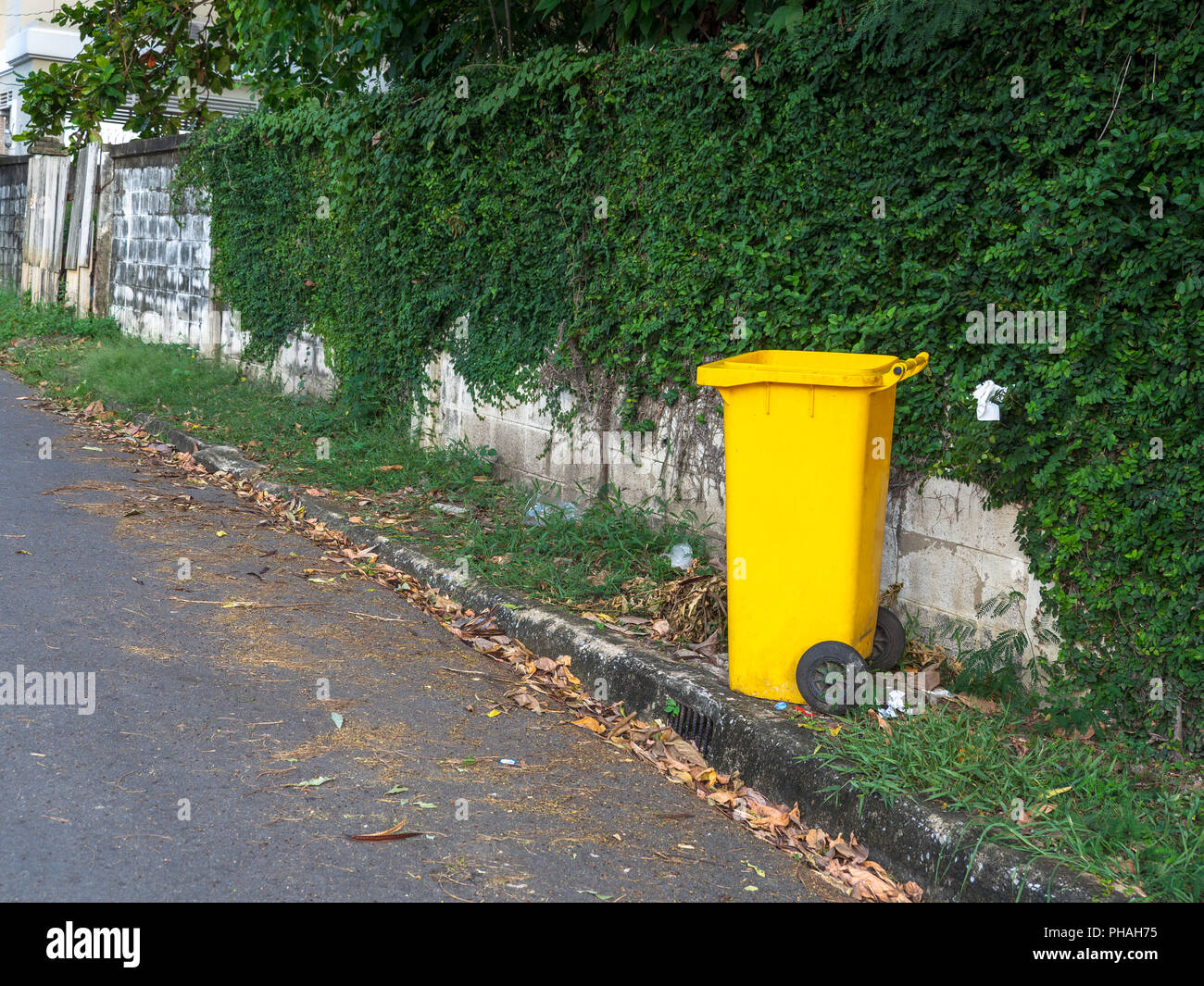 Yellow bins are placed on the side of the road in the village. Trash is ...
