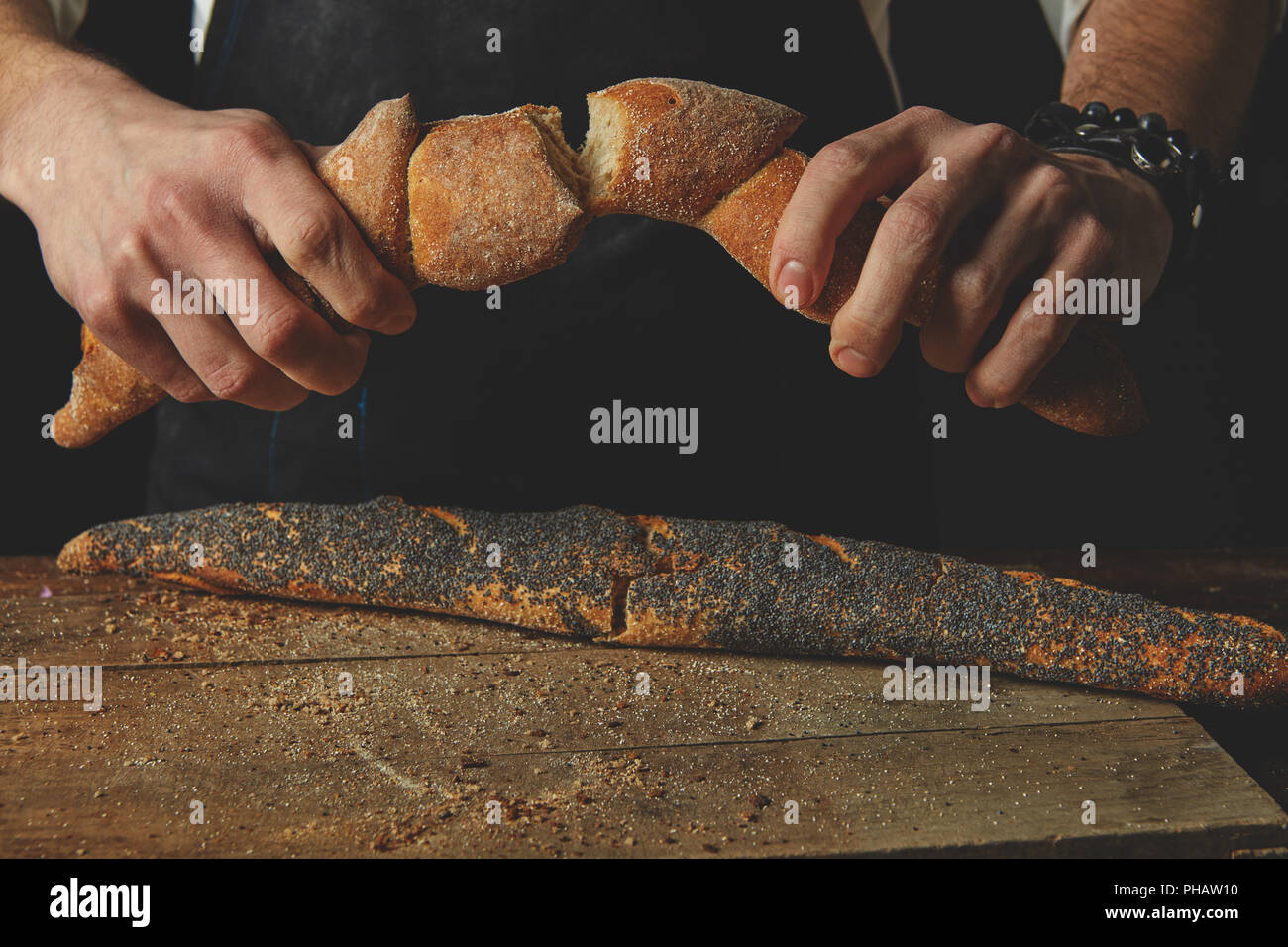 Hand breaks baguette Stock Photo - Alamy