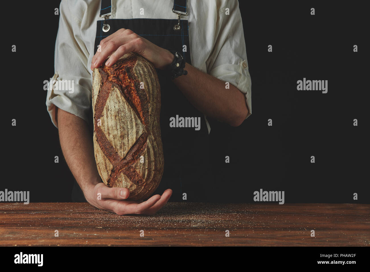 Baker's hands hold an oval bread Stock Photo - Alamy