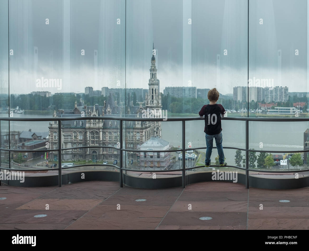 Boy looking through the window of the MAS museum on a rainy day, Sunday ...