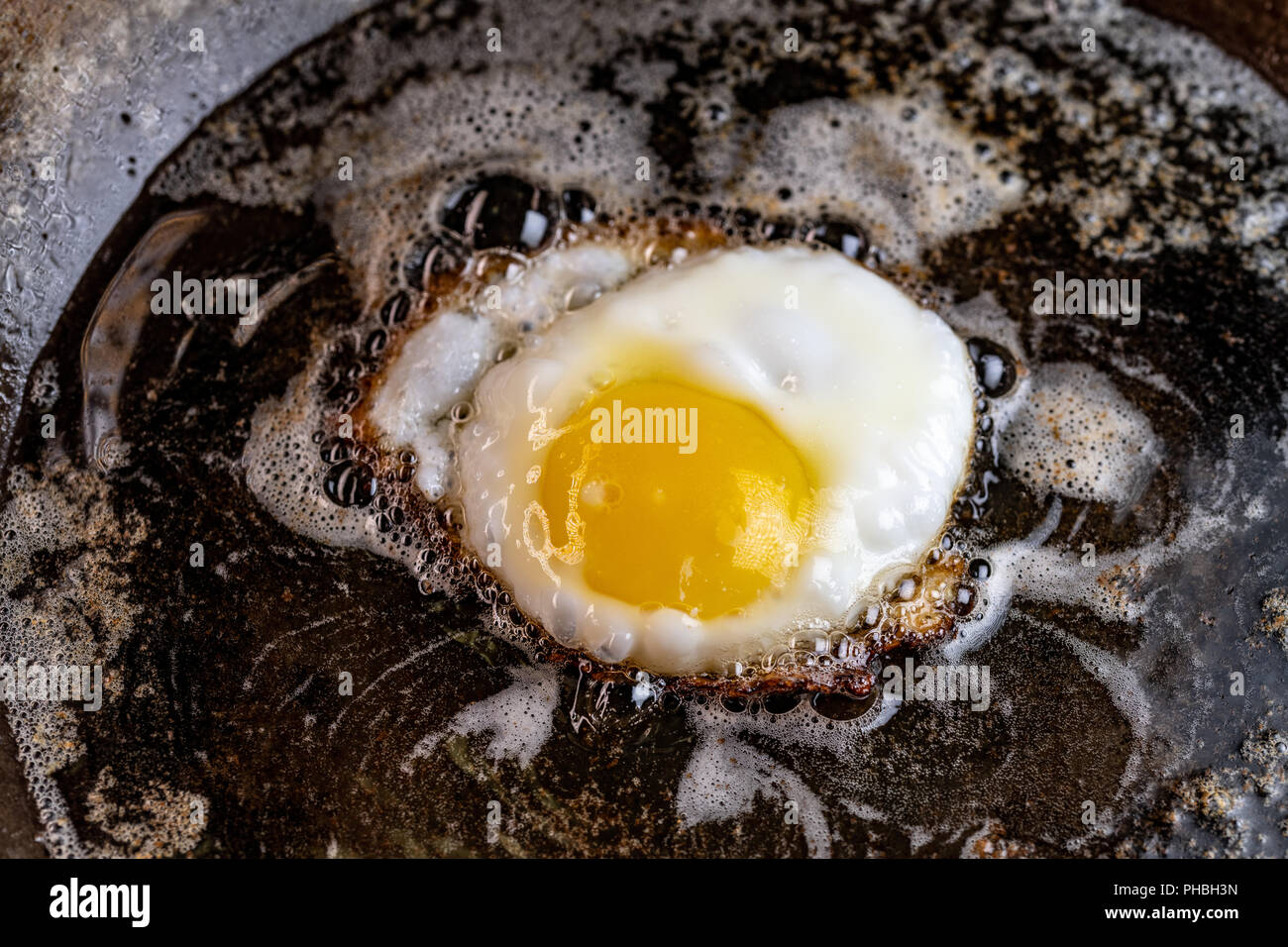 An egg frying in butter and oil in a carbon steel skillet Stock Photo ...