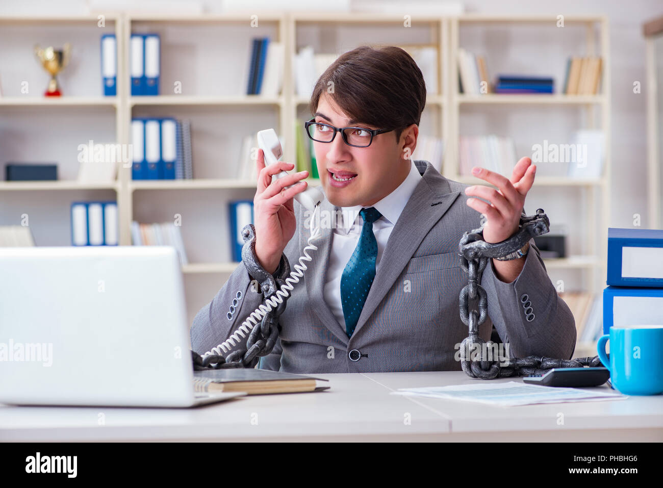Businessman tied with chains to his work Stock Photo - Alamy