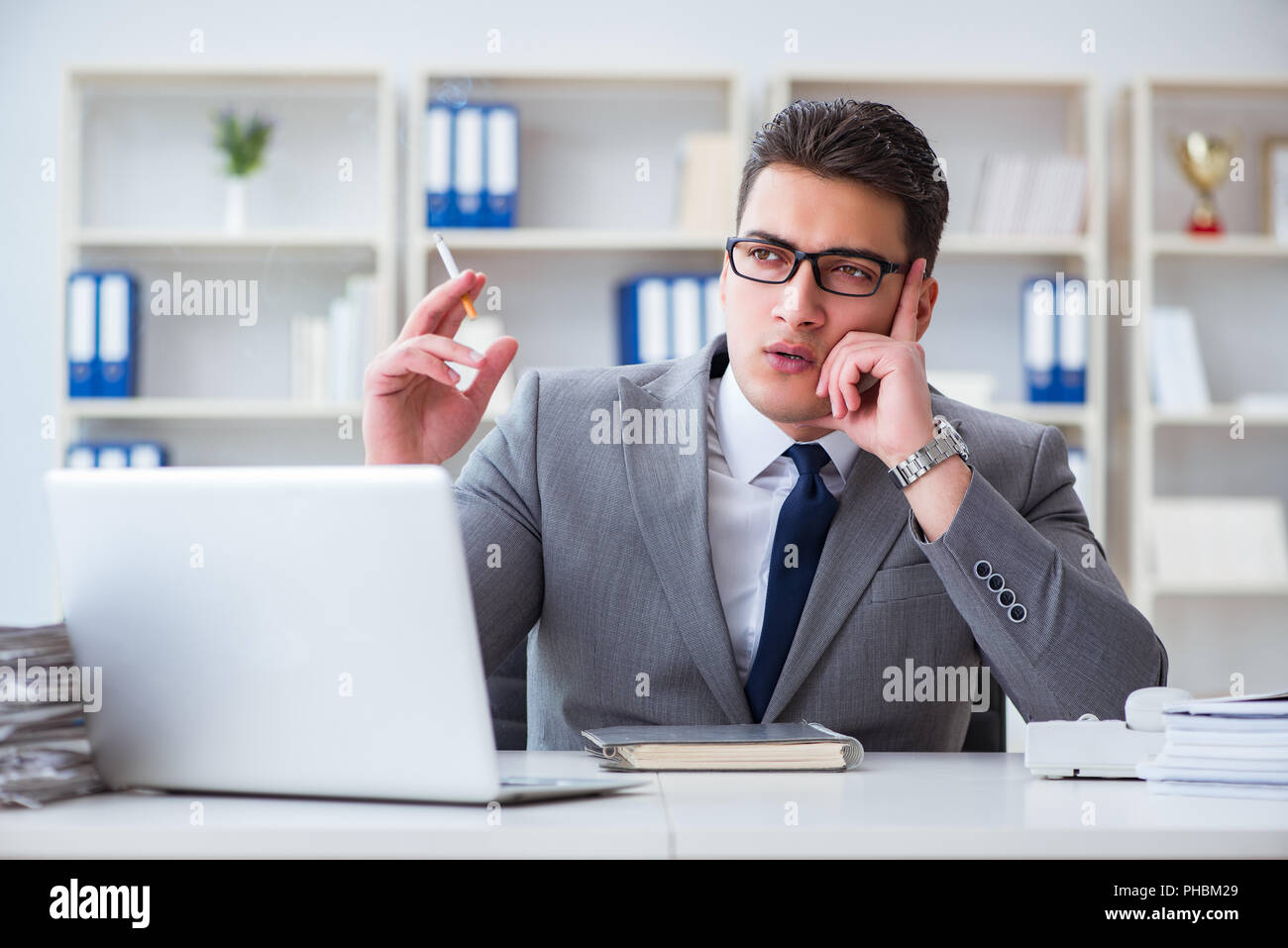 Businessman smoking in office at work Stock Photo - Alamy