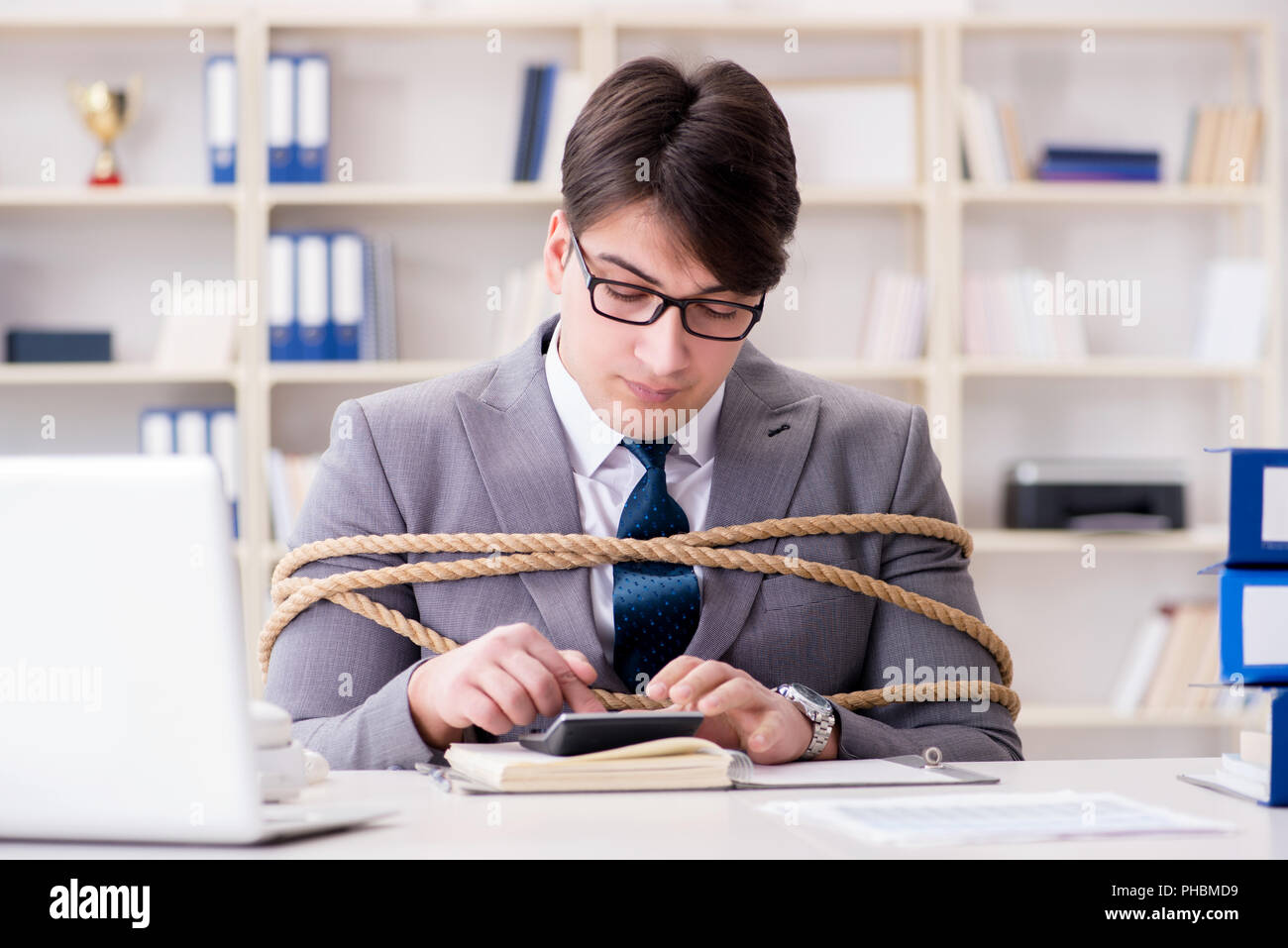 Businessman tied up with rope in office Stock Photo - Alamy