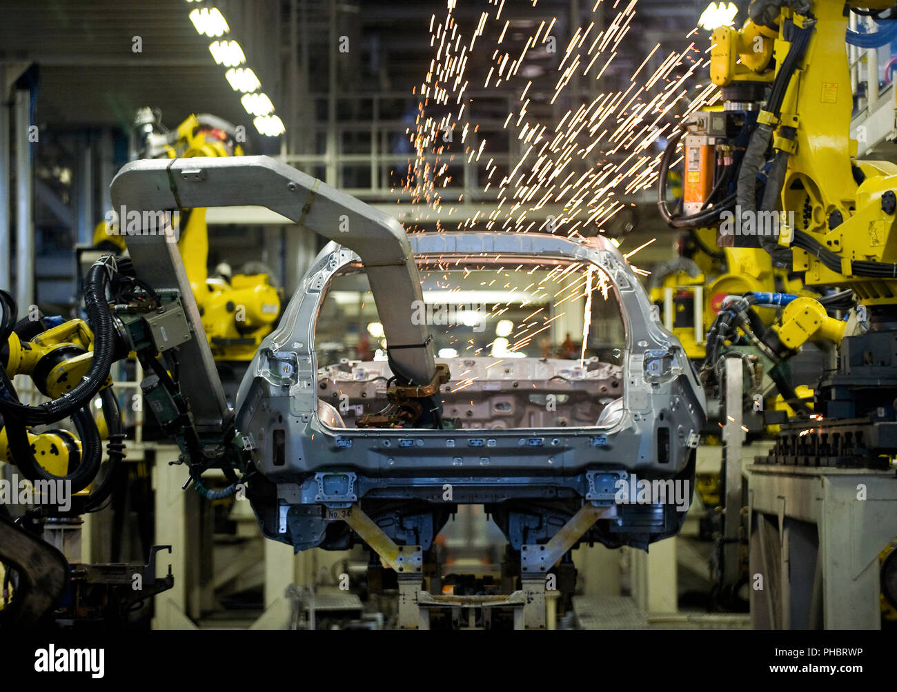 Robots get to work on the body of a new Nissan Motor Co. vehicle at the ...