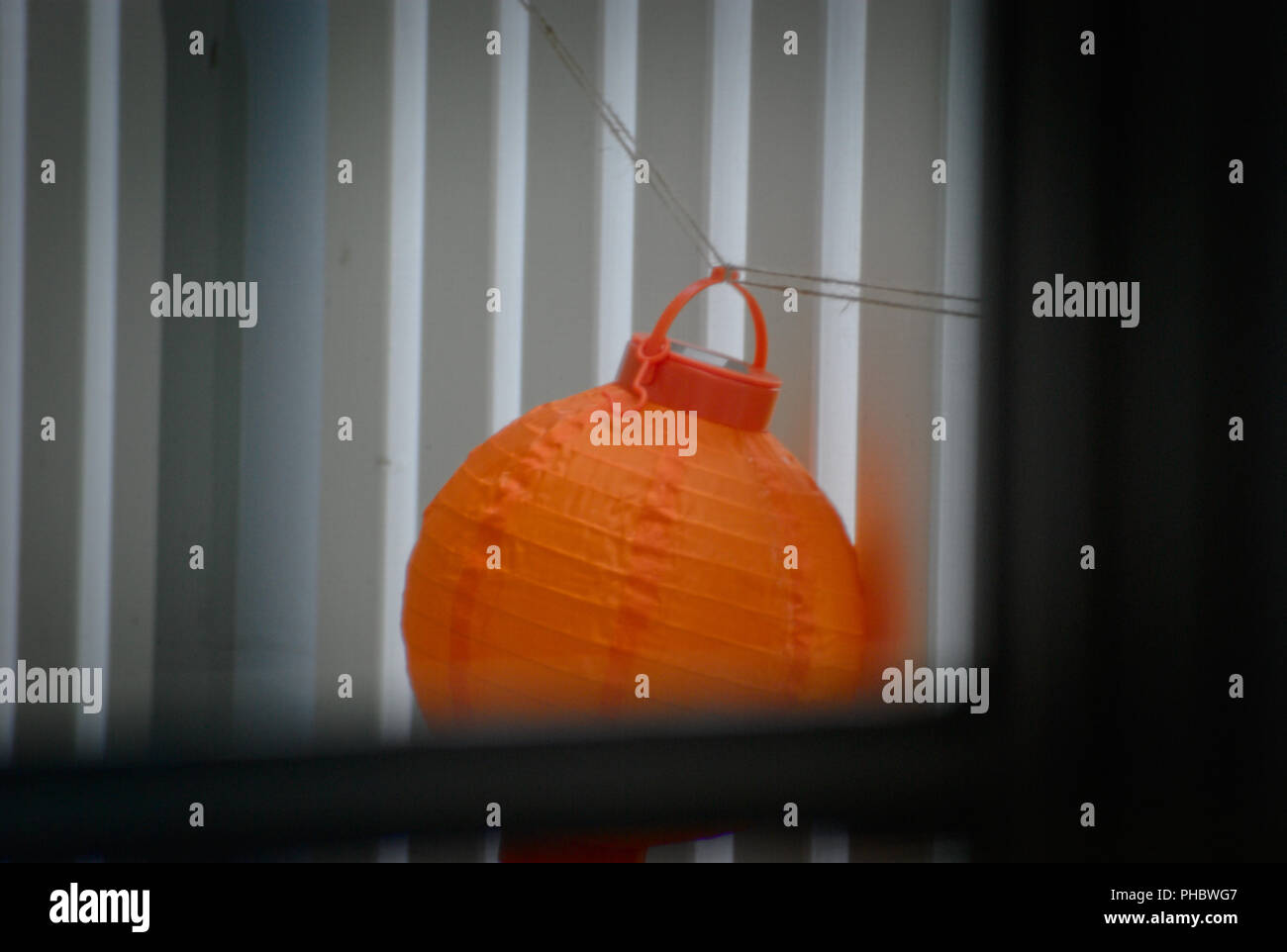 a lonely orange lantern is hanging on a white balcony in sad mood after ...