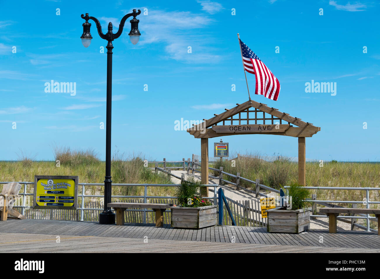 Wooden exits from the boardwalk to the beach with US flag, ocean ave ...