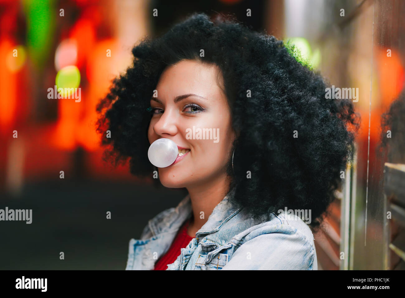 Young pretty woman with very curly afro hair inflates a bubble ball of ...