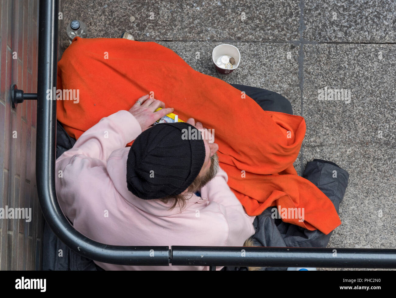 a homeless man sitting on some steps next to tower bridge in central ...