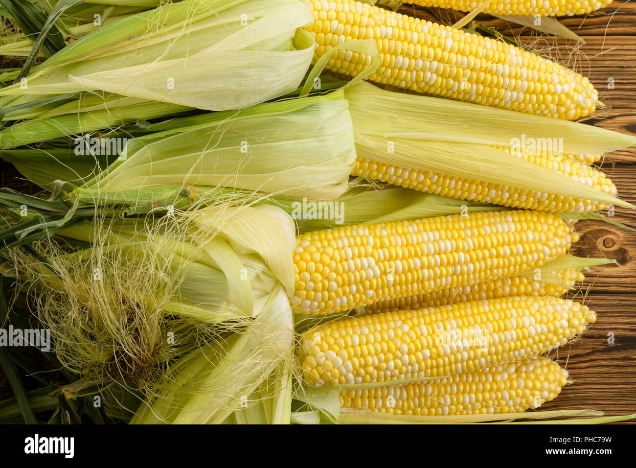 Pile of fresh yellow sweetcorn on the cob with the leaves peeled back ...