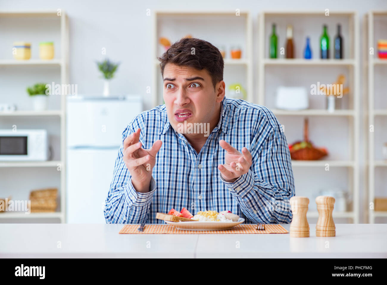 Young husband eating tasteless food at home for lunch Stock Photo - Alamy