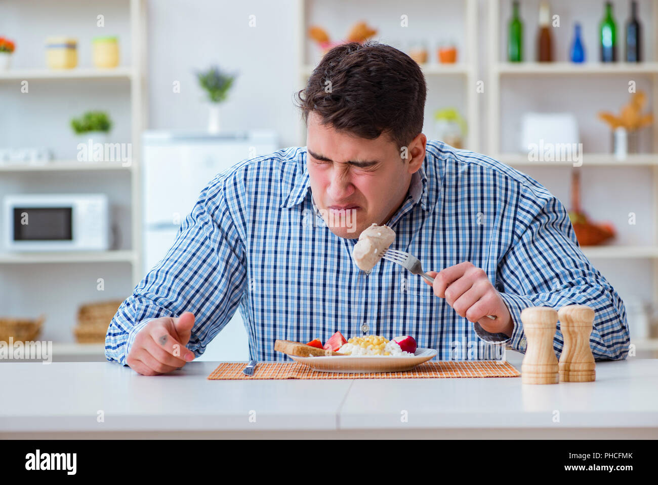 Man eating tasteless food at home for lunch Stock Photo - Alamy
