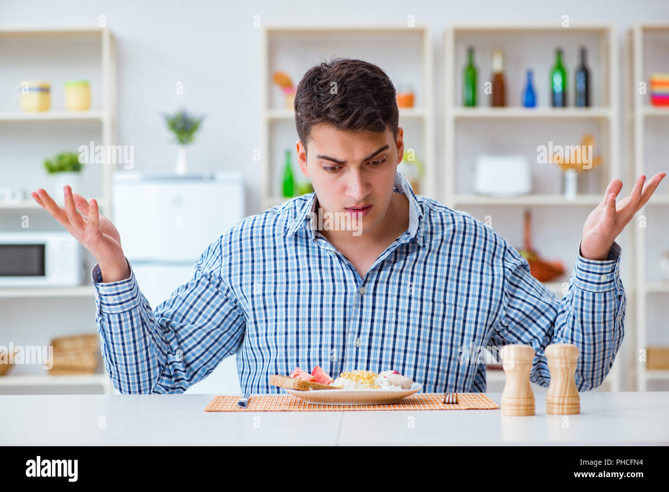 Young husband eating tasteless food at home for lunch Stock Photo - Alamy