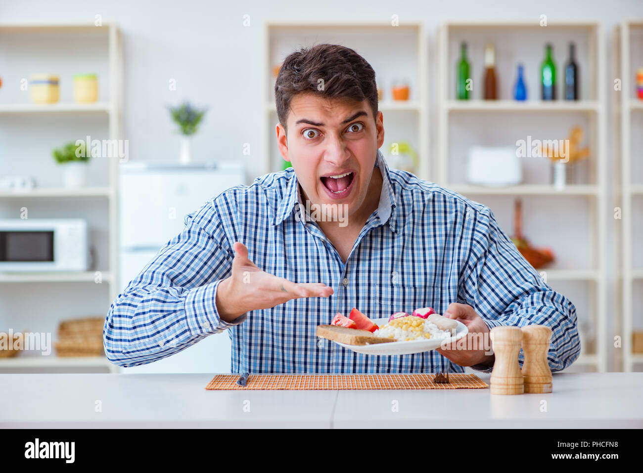 Young husband eating tasteless food at home for lunch Stock Photo - Alamy