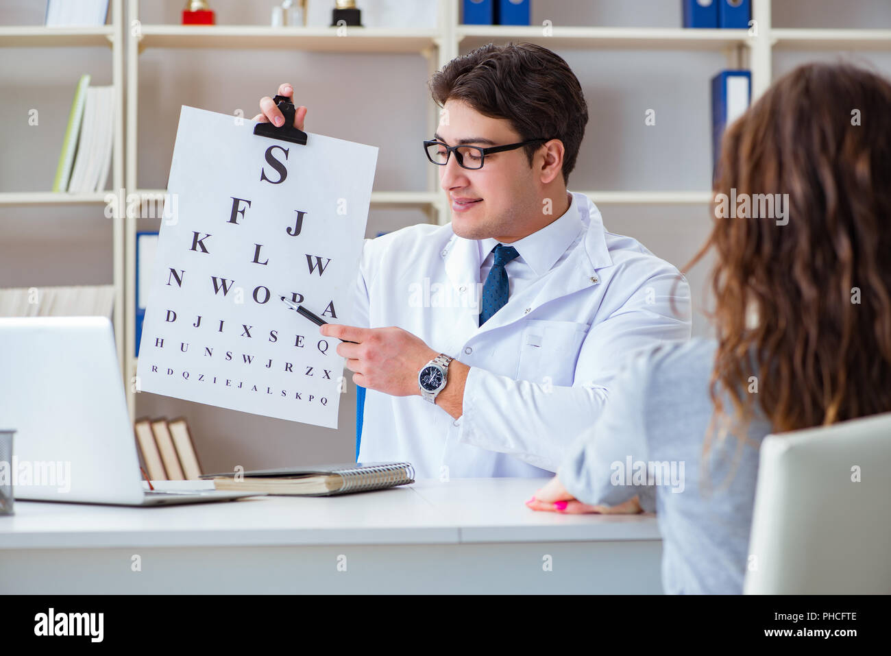 Doctor optician with letter chart conducting an eye test check Stock ...