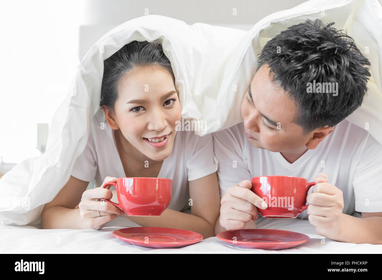 Smiling couple having breakfast on bed at home couple hi-res stock ...