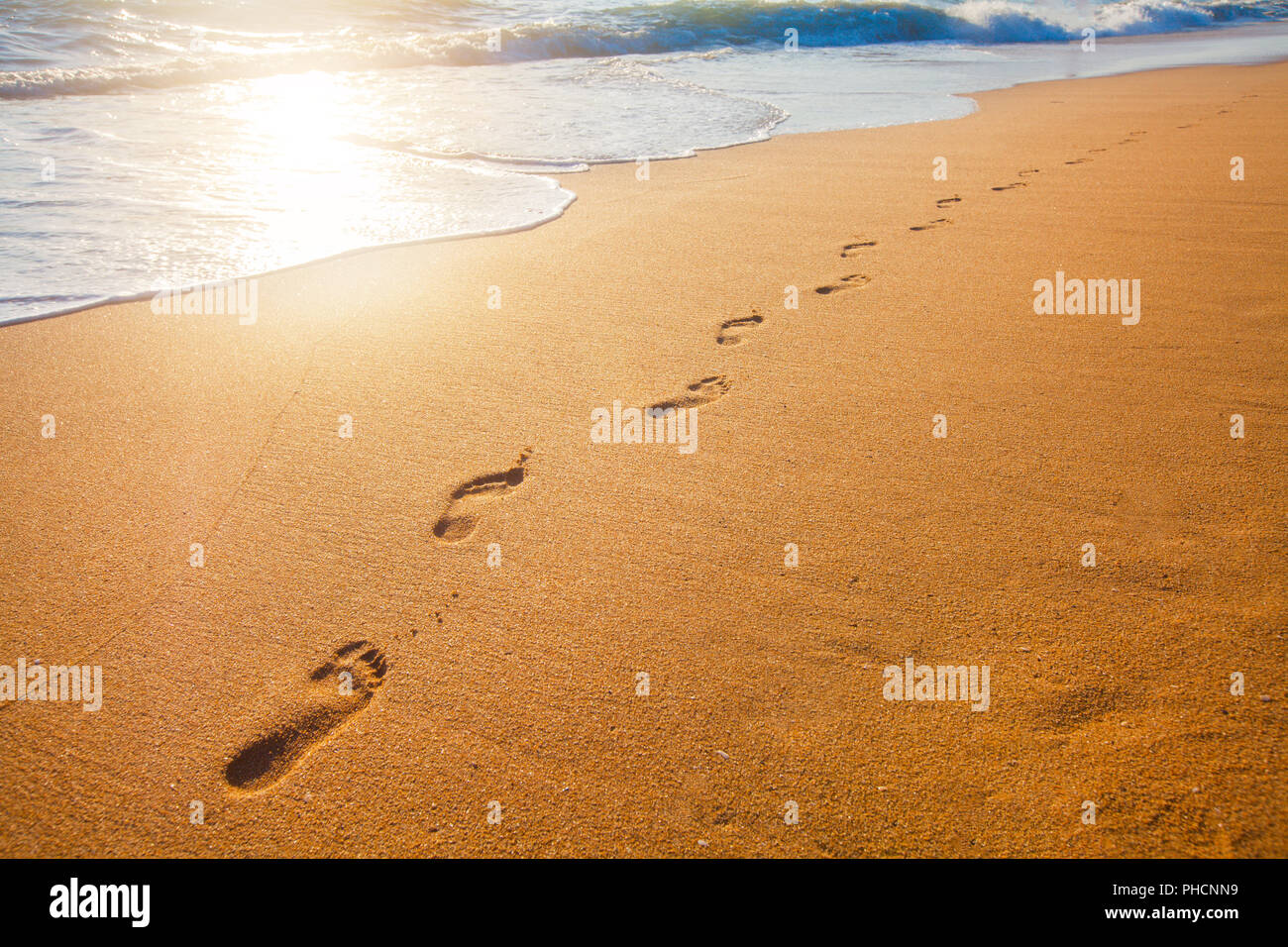 beach, wave and footprints at sunset time Stock Photo - Alamy