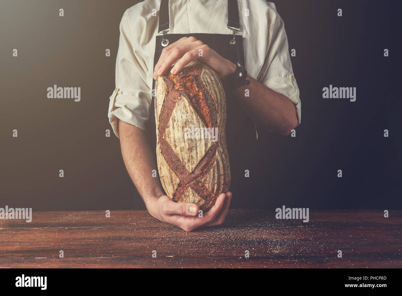 Baker's hands hold an oval bread Stock Photo - Alamy