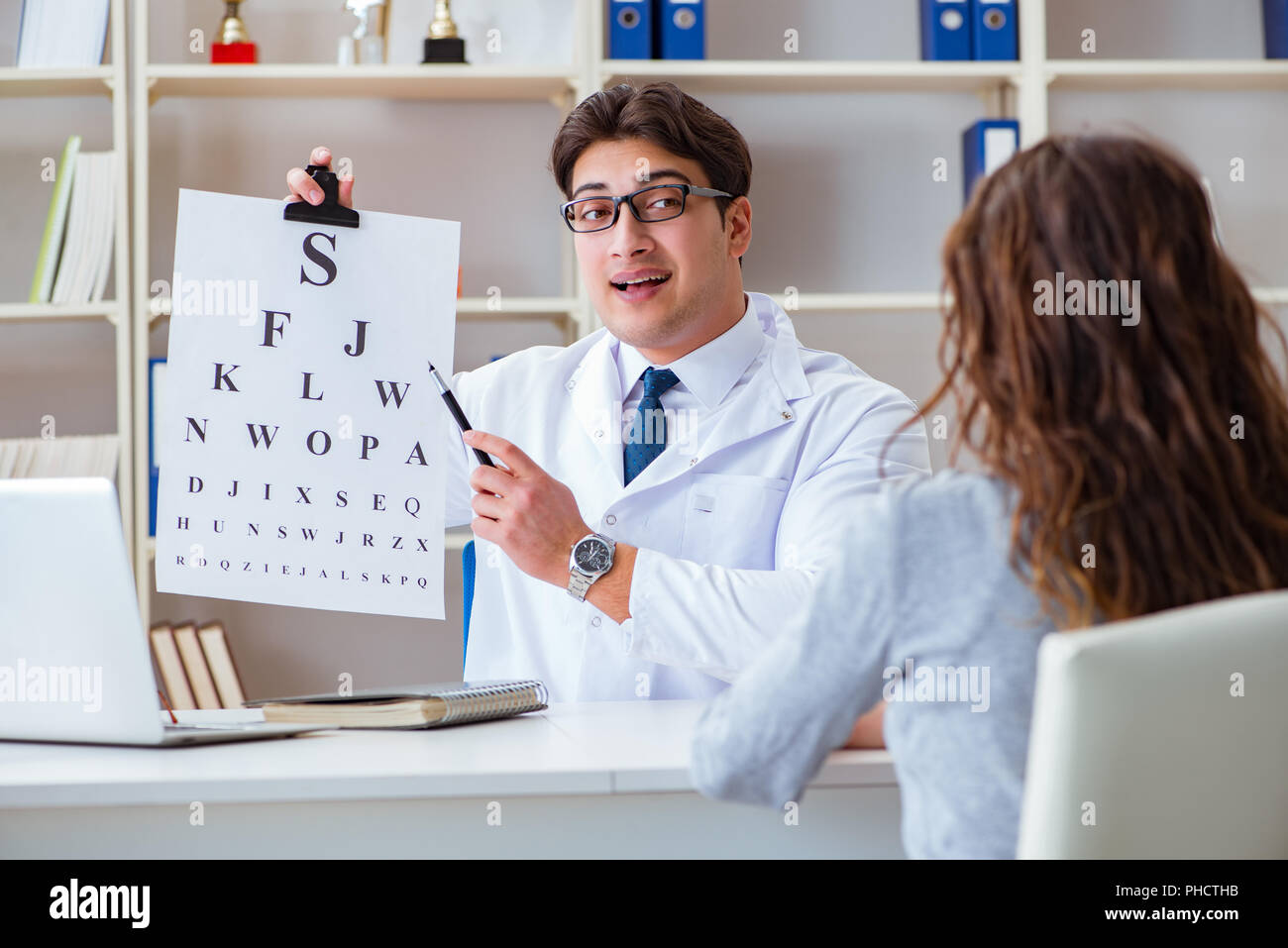 Doctor optician with letter chart conducting an eye test check Stock ...