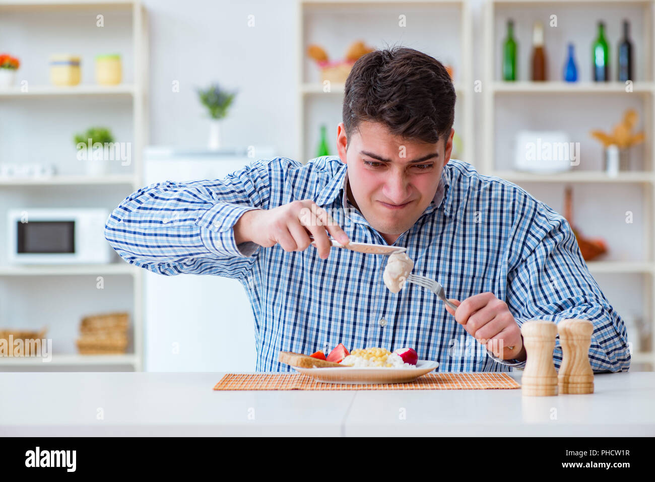 Man eating tasteless food at home for lunch Stock Photo - Alamy