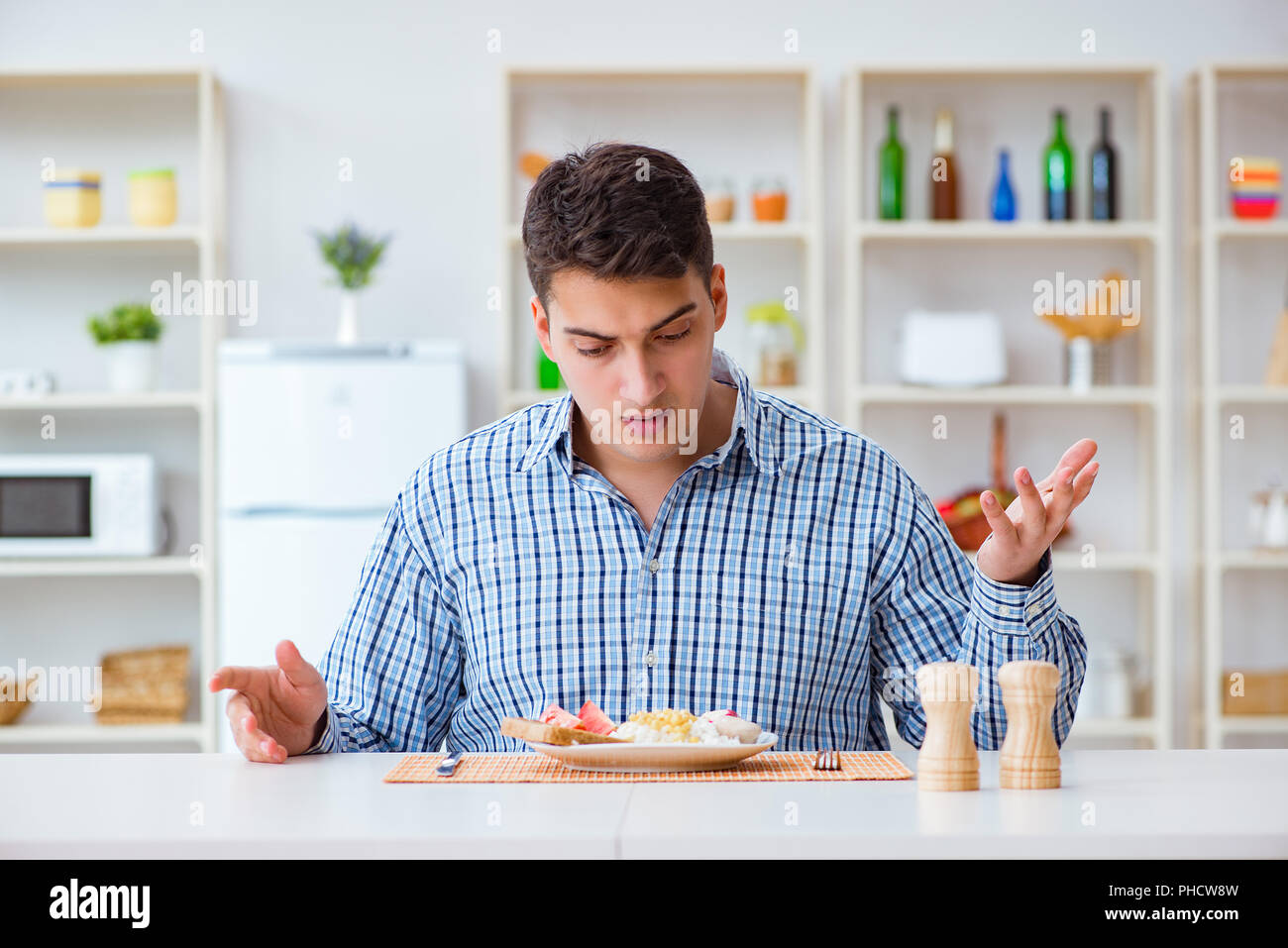 Young husband eating tasteless food at home for lunch Stock Photo - Alamy