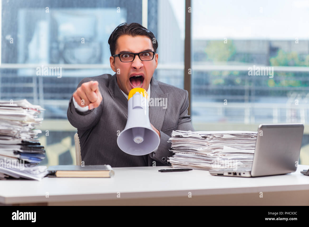 Angry businessman with loudspeaker in the office Stock Photo - Alamy