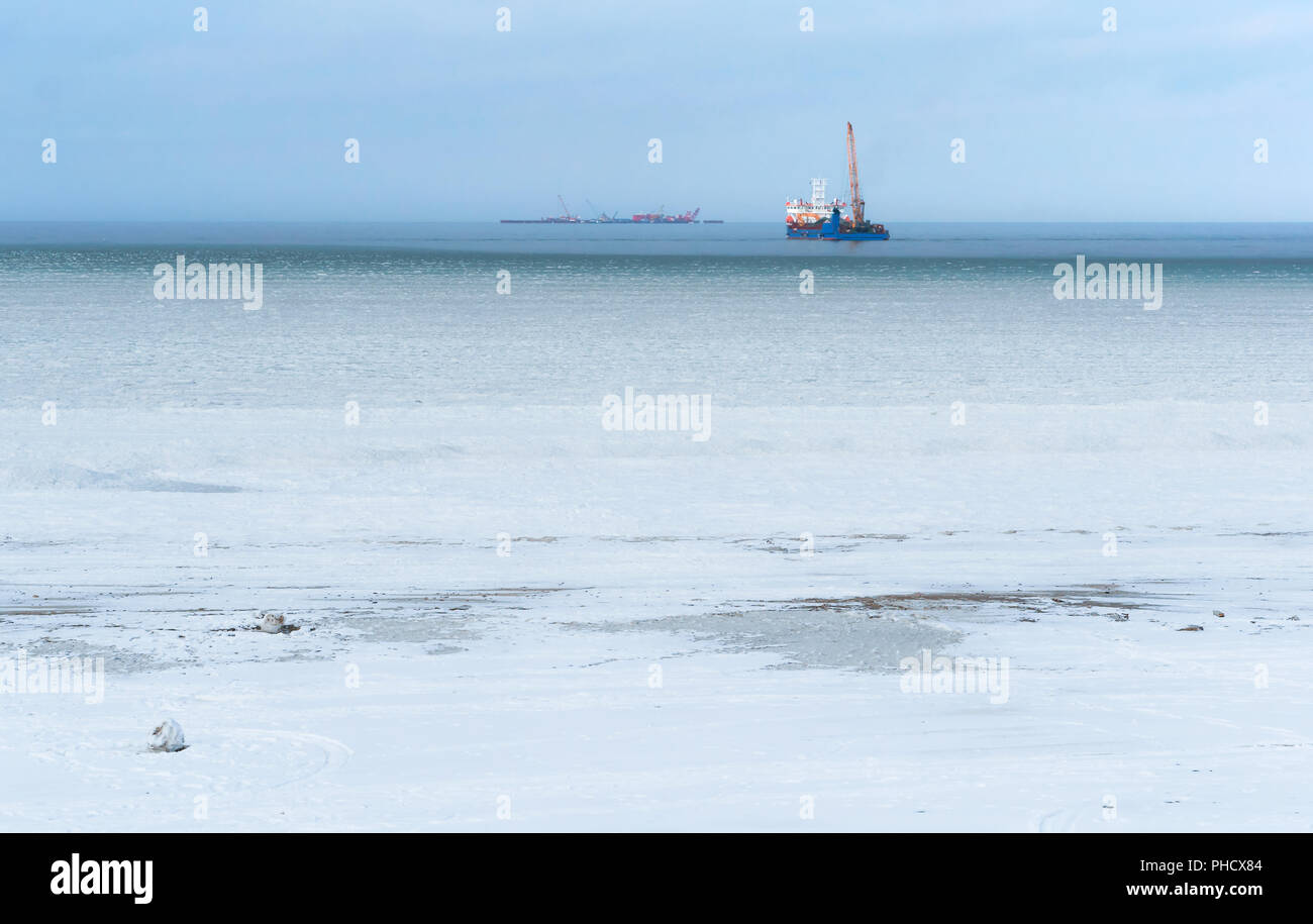 ice sludge in the sea, oil platform in the winter sea on the horizon ...