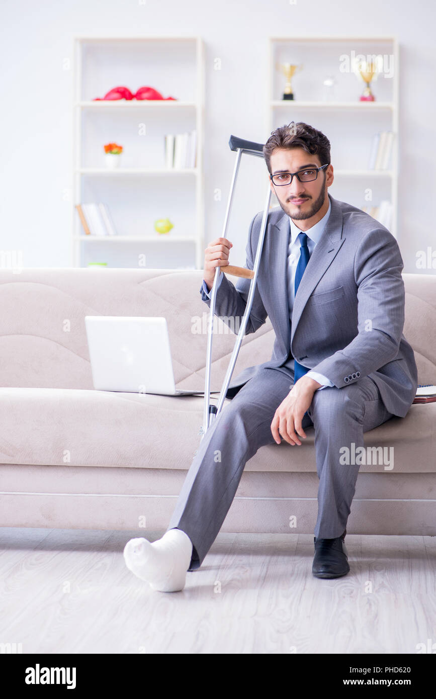 Businessman with crutches and broken leg at home working Stock Photo ...