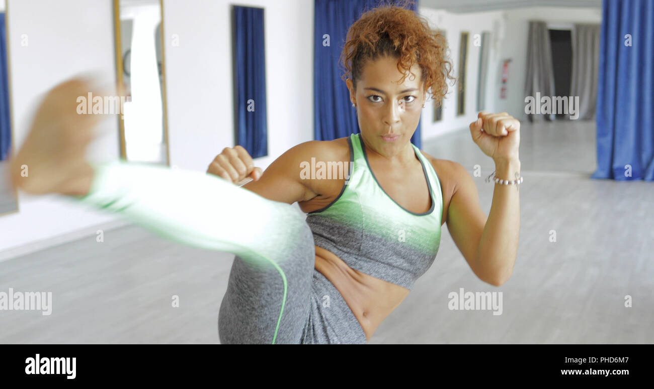 Sportive woman kicking with leg Stock Photo - Alamy