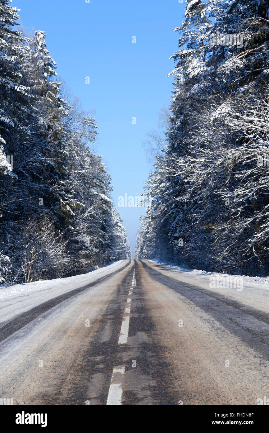 asphalt road with white road markings under the snow, part of the snow ...