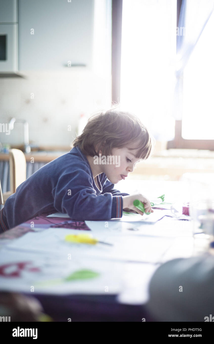 child colors and draws at the kitchen table Stock Photo - Alamy
