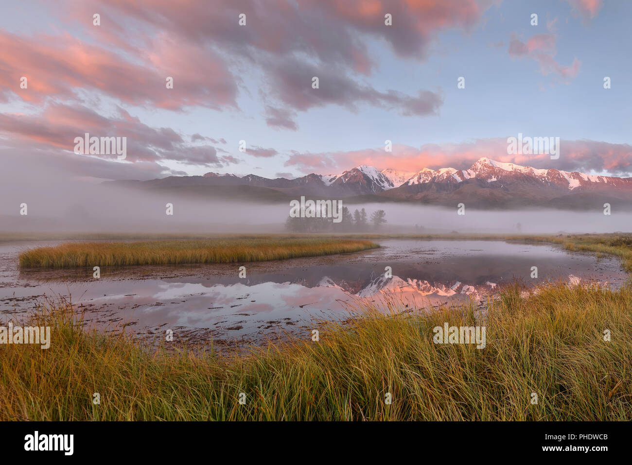 Amazing pink sunrise with a beautiful mist over the lake, mountains ...