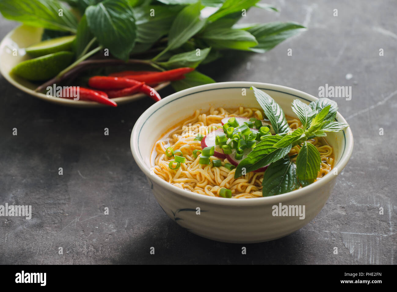 Instant noodles in bowl with fresh herbs, garnish of cilantro and Asian ...