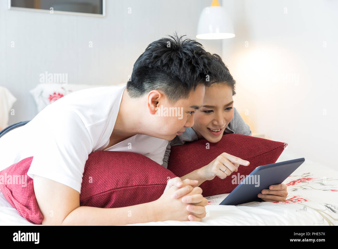 Couples lying using tablet on bed Stock Photo - Alamy