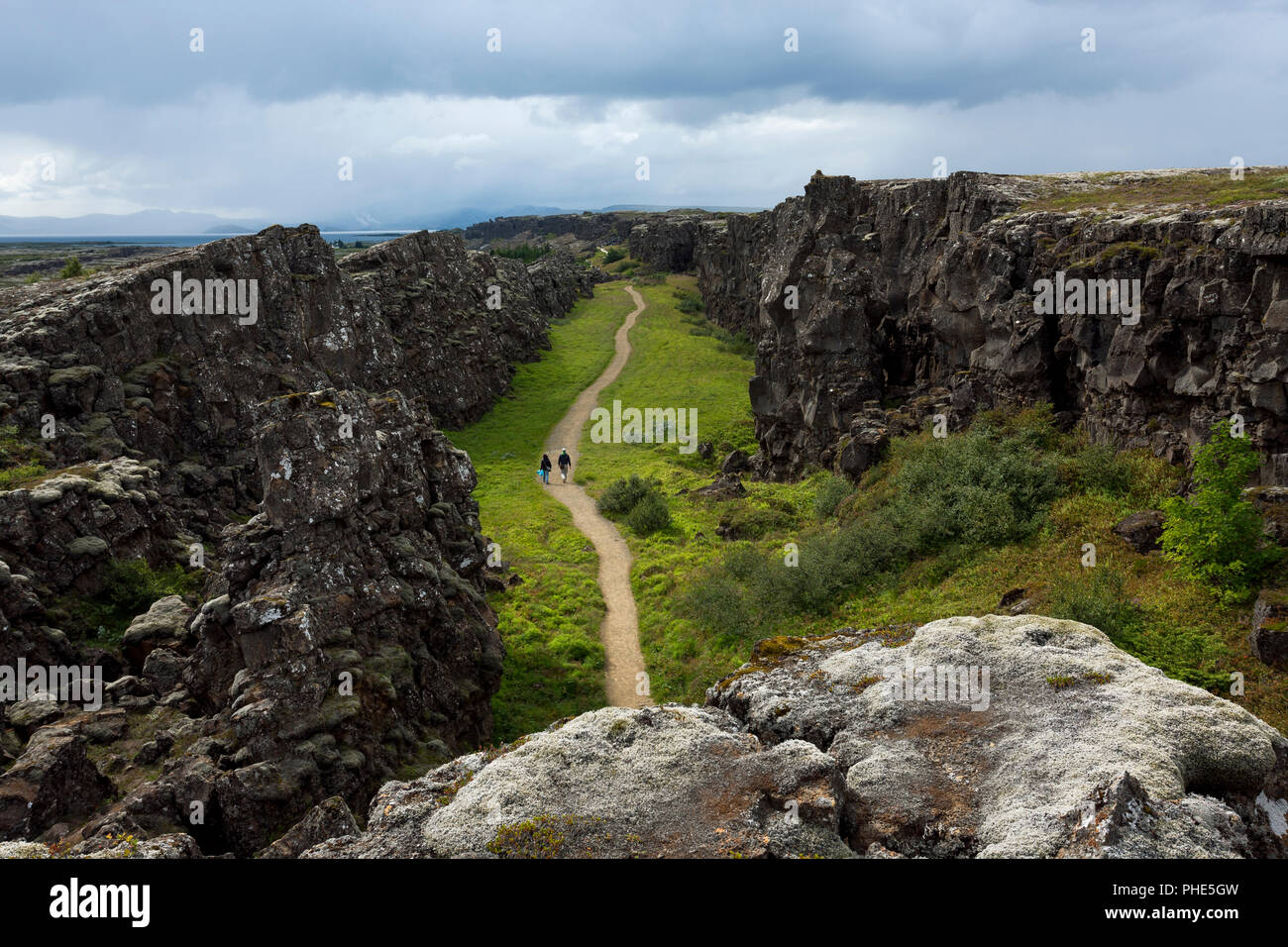 Two people walk along the Mid-Atlantic Ridge in Þingvellir, Iceland ...