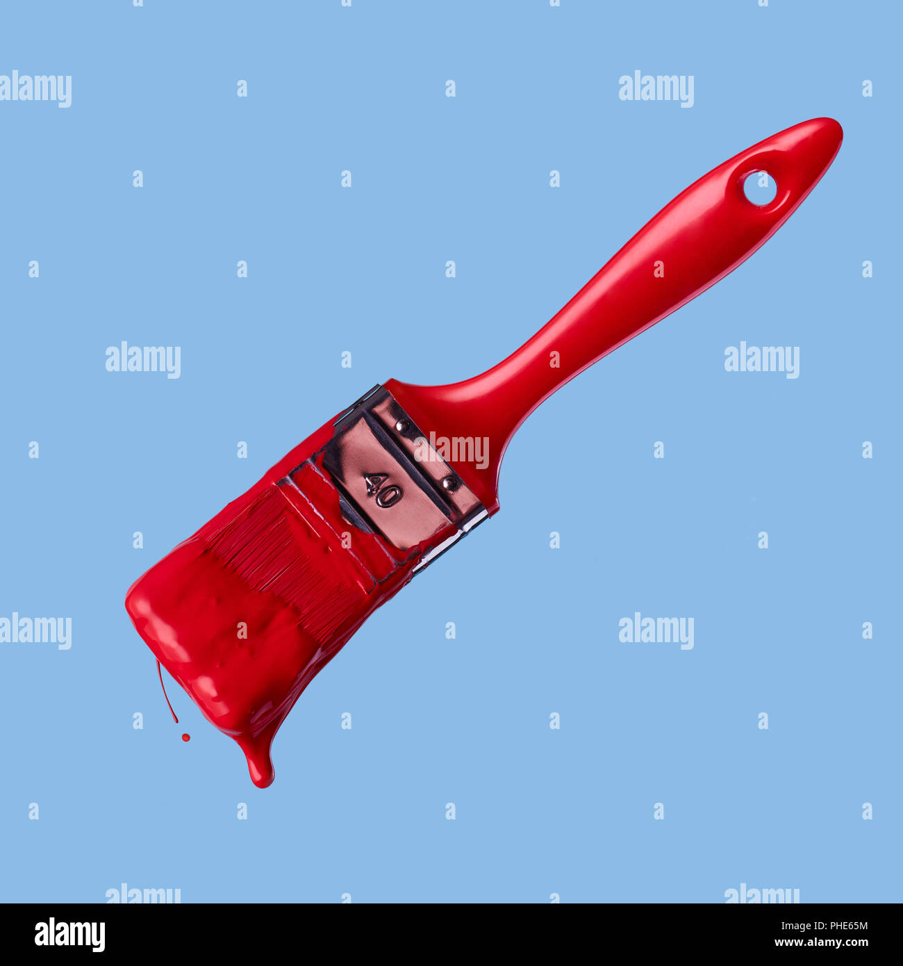 red paintbrush isolated on a blue background Stock Photo - Alamy