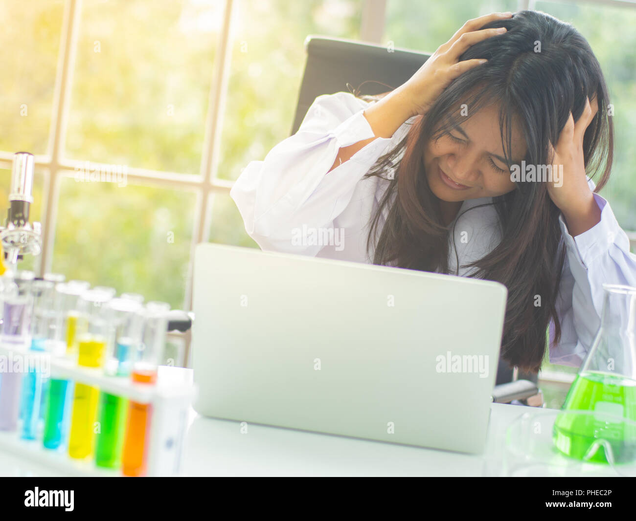 Young asian female scientist sitting on chair holding her head with ...