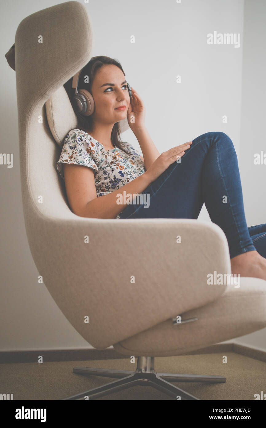 Pretty, young woman listening to her favorite music on hi-fi headphones ...
