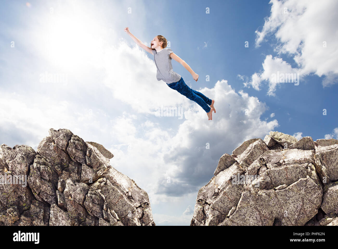 Little cute girl flying like a supergirl from one rock to another Stock ...