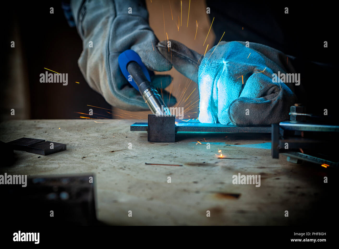 Strong man welder in work clothes hard working and welds with a welding ...