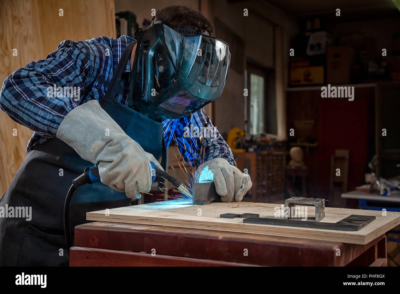Strong man welder in work clothes hard working and welds with a welding ...