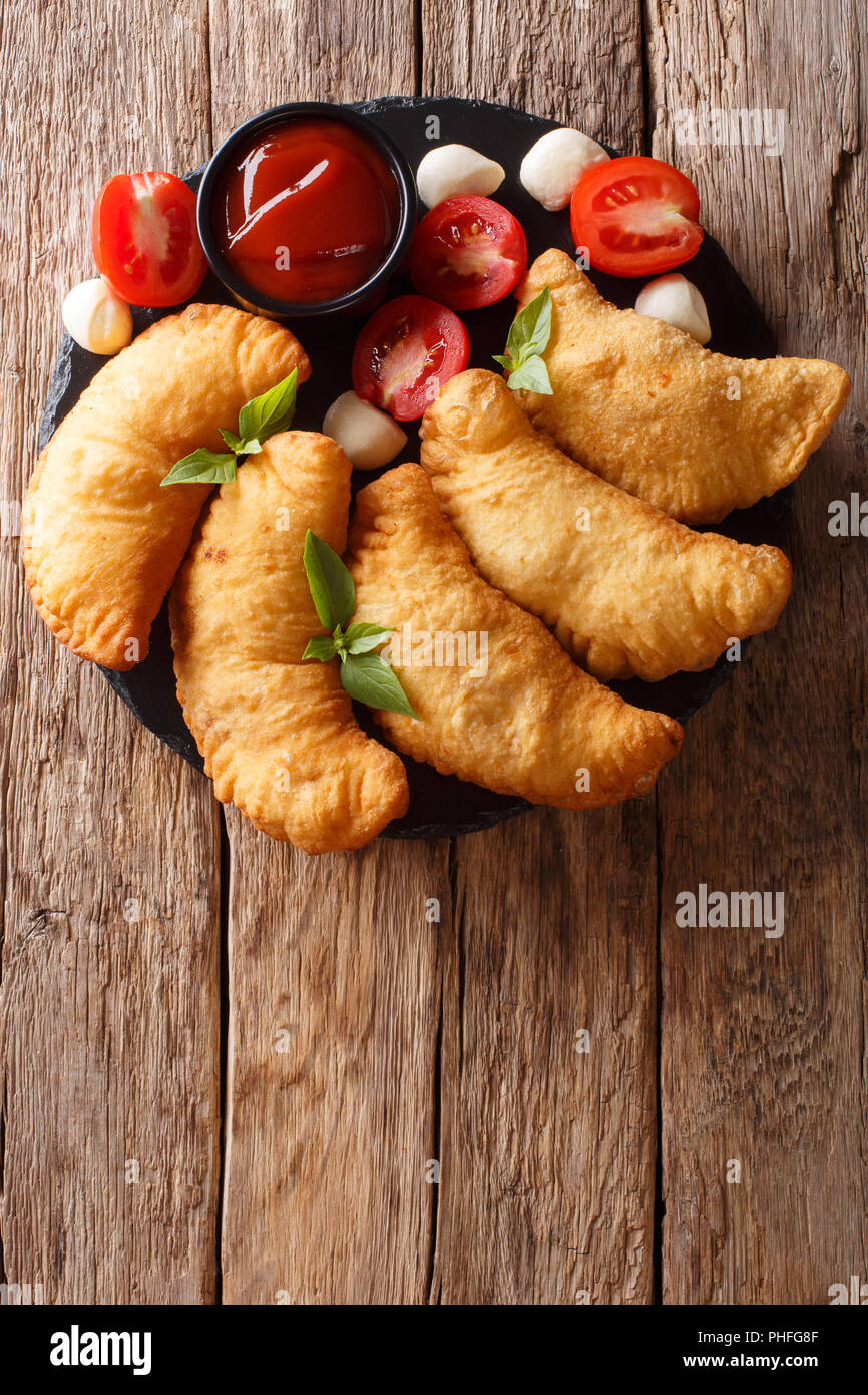fried panzerotti with a filling of tomatoes, herbs and mozzarella close ...