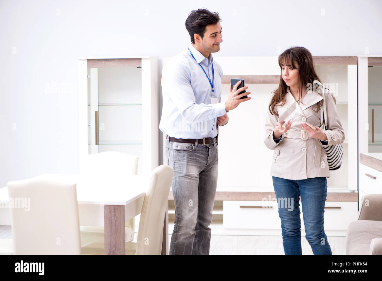 Salesman explaining to woman customer at furniture store Stock Photo ...