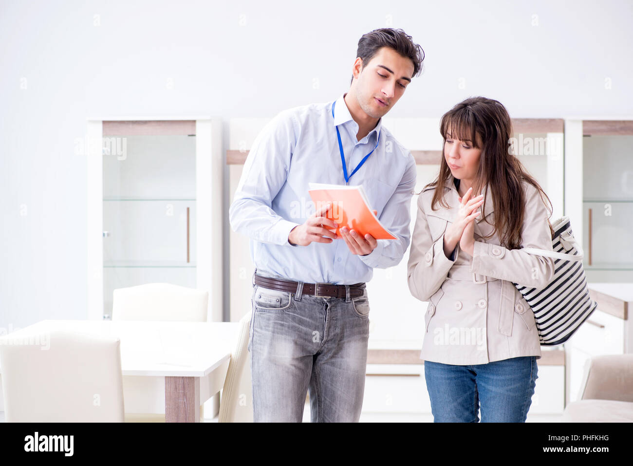 Salesman explaining to woman customer at furniture store Stock Photo ...