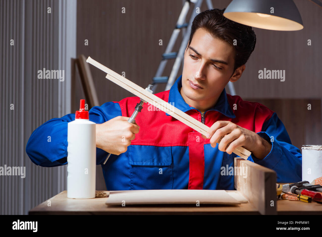Young man gluing wood pieces together in DIY concept Stock Photo - Alamy