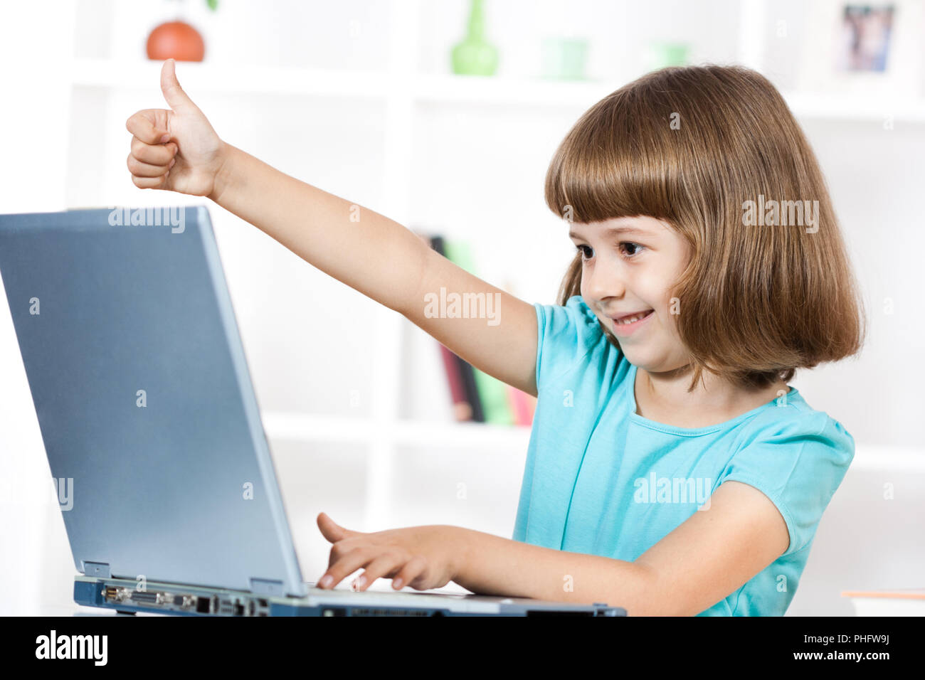 Little girl with laptop showing thumb up Stock Photo - Alamy