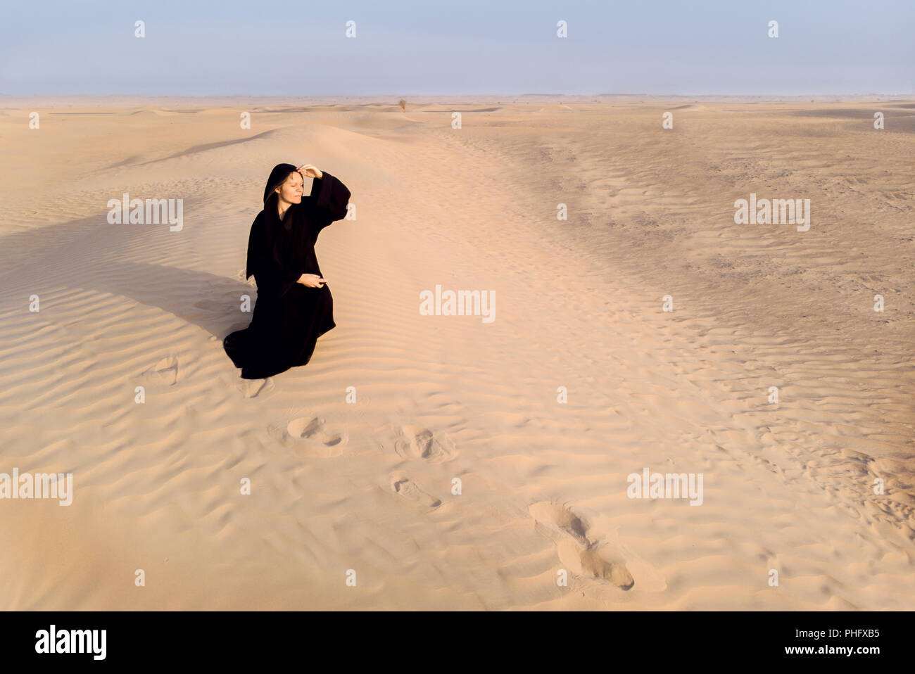 woman in a traditional emirati dress called abaya in a desert near ...