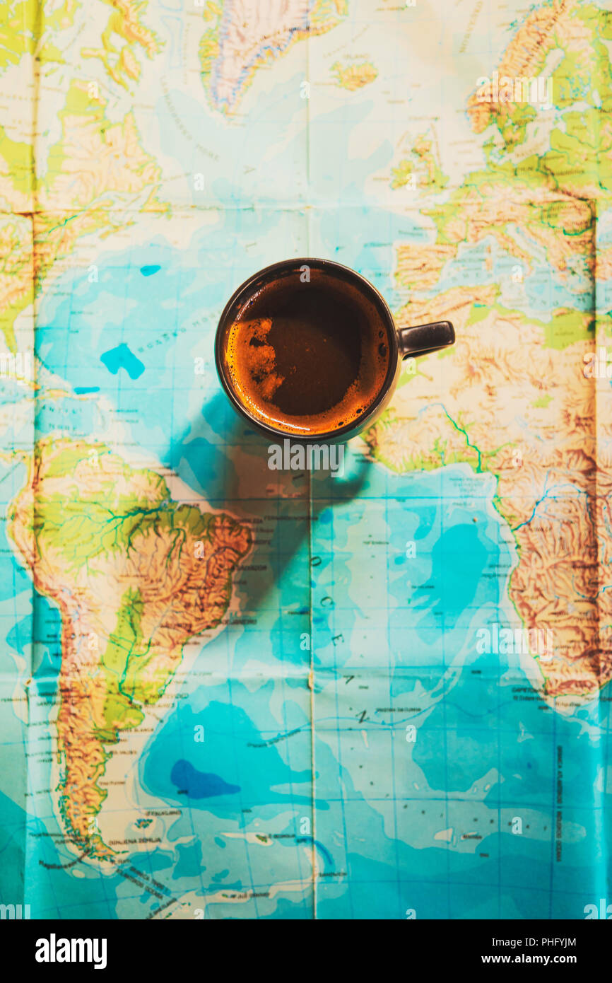 Fresh cup of coffee with world map in the background; conceptual image ...