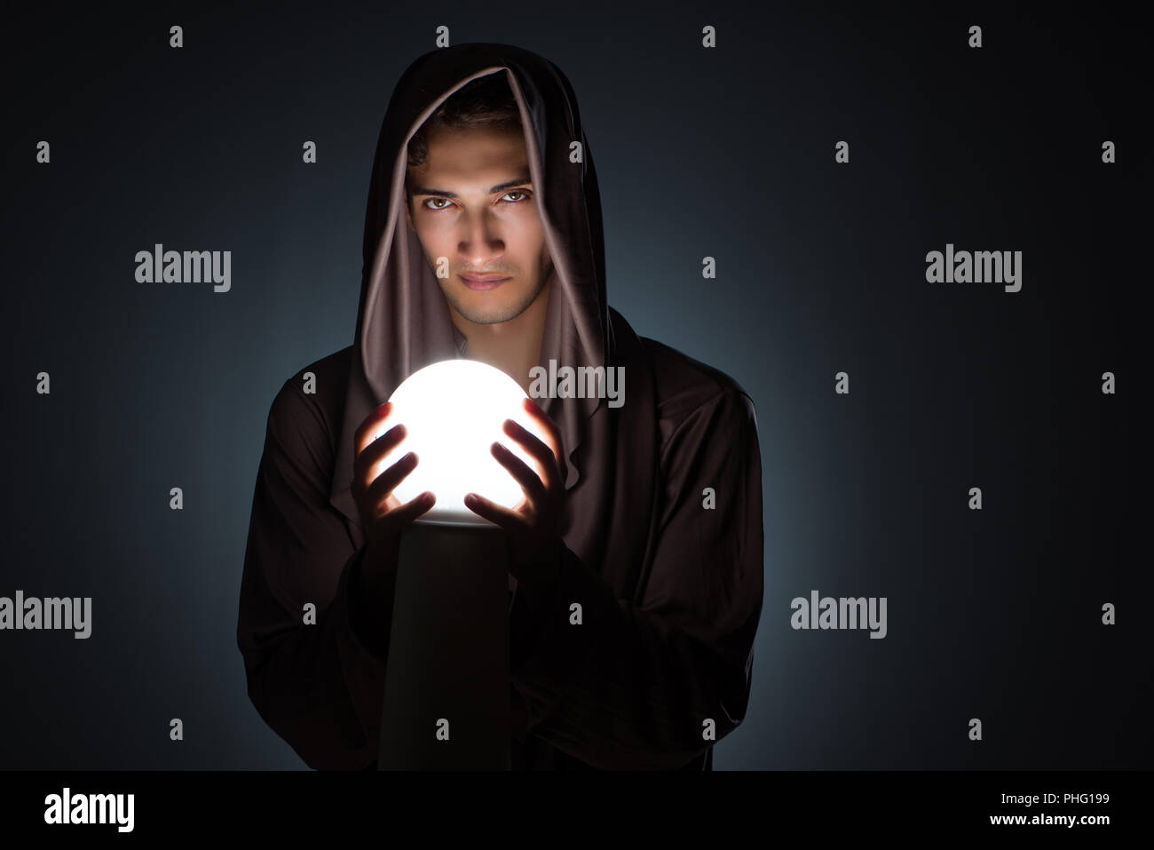 Young wizard with crystal ball in dark room Stock Photo - Alamy